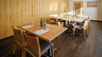 Sala de conferências com uma mesa comprida, cadeiras e painéis de madeira.