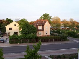 Uma área residencial com duas casas, uma bege e outra marrom, com uma rua na frente.