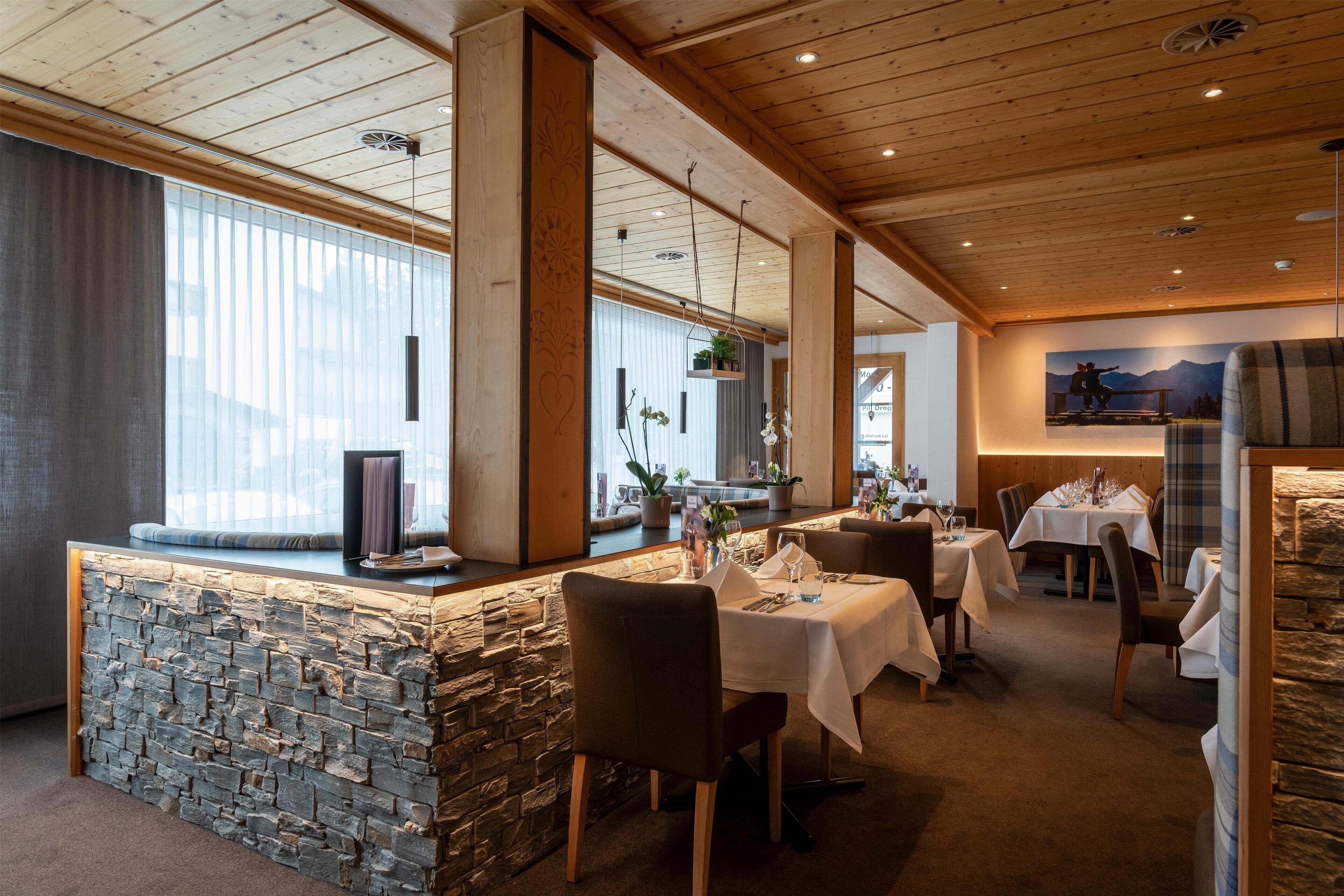 Um restaurante com paredes de pedra, vigas de madeira no teto e mesas preparadas para refeições.