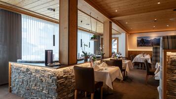 Um restaurante com paredes de pedra, vigas de madeira no teto e mesas preparadas para refeições.