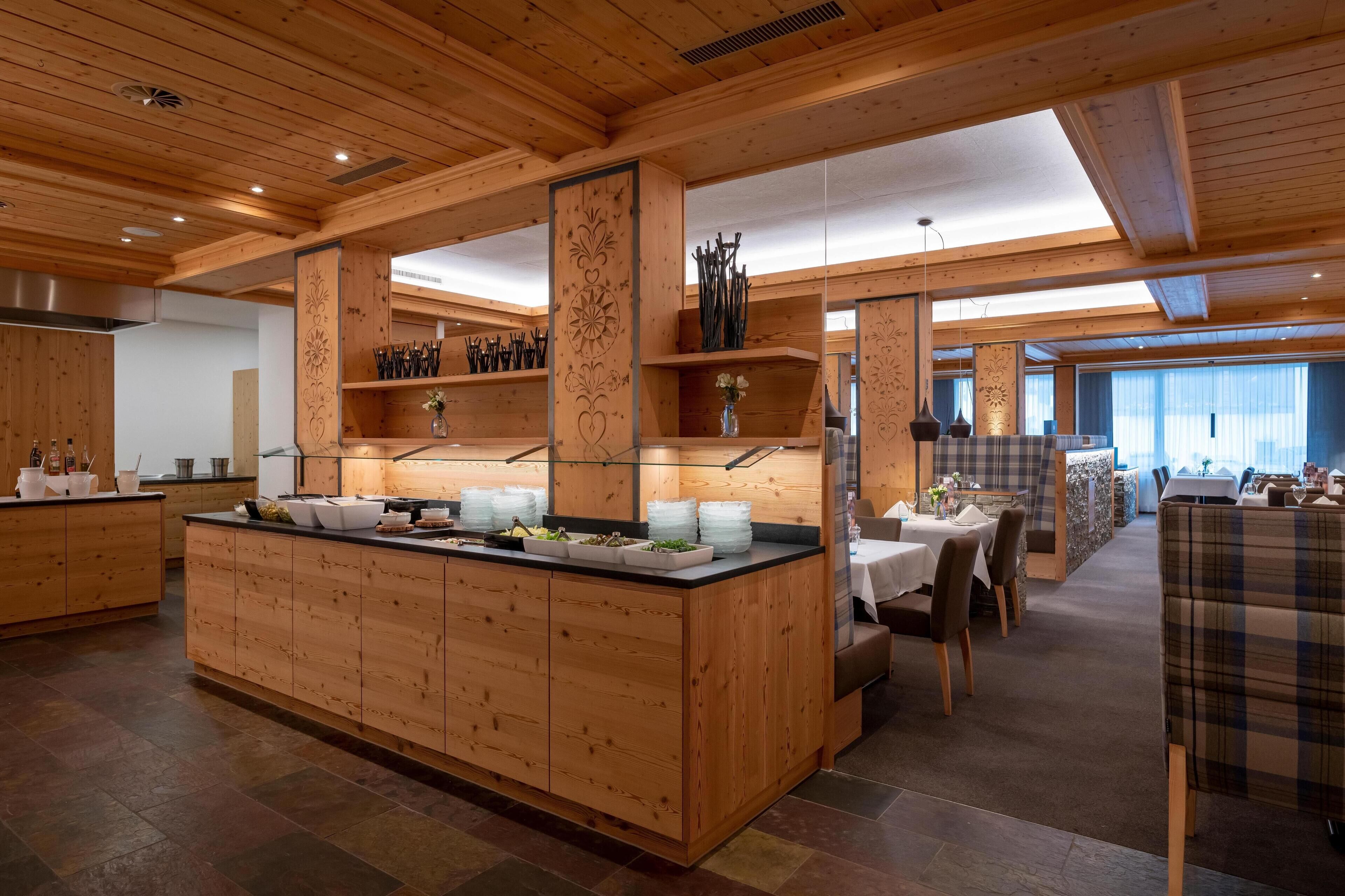 Interior de madeira com ilha central, sala de jantar e cozinha.