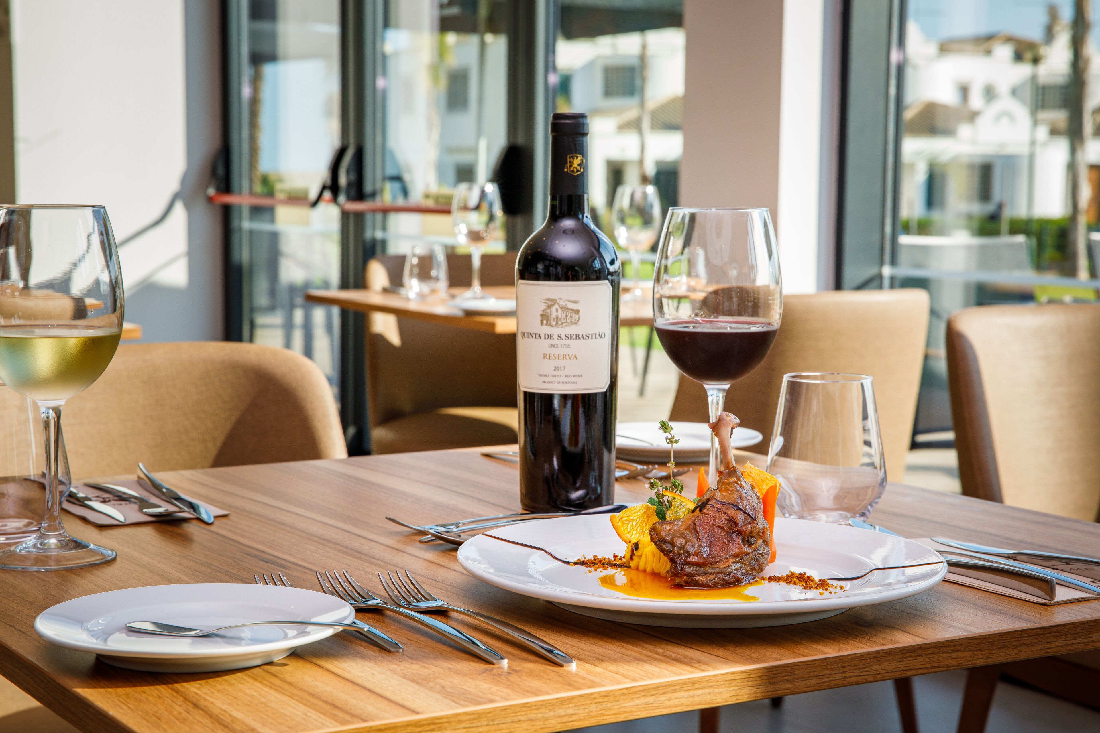 Uma mesa de jantar com uma garrafa de vinho, uma taça de vinho tinto e um prato de comida.