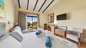 Quarto de hotel com duas camas, uma escrivaninha, uma cadeira, televisão e varanda com vista.