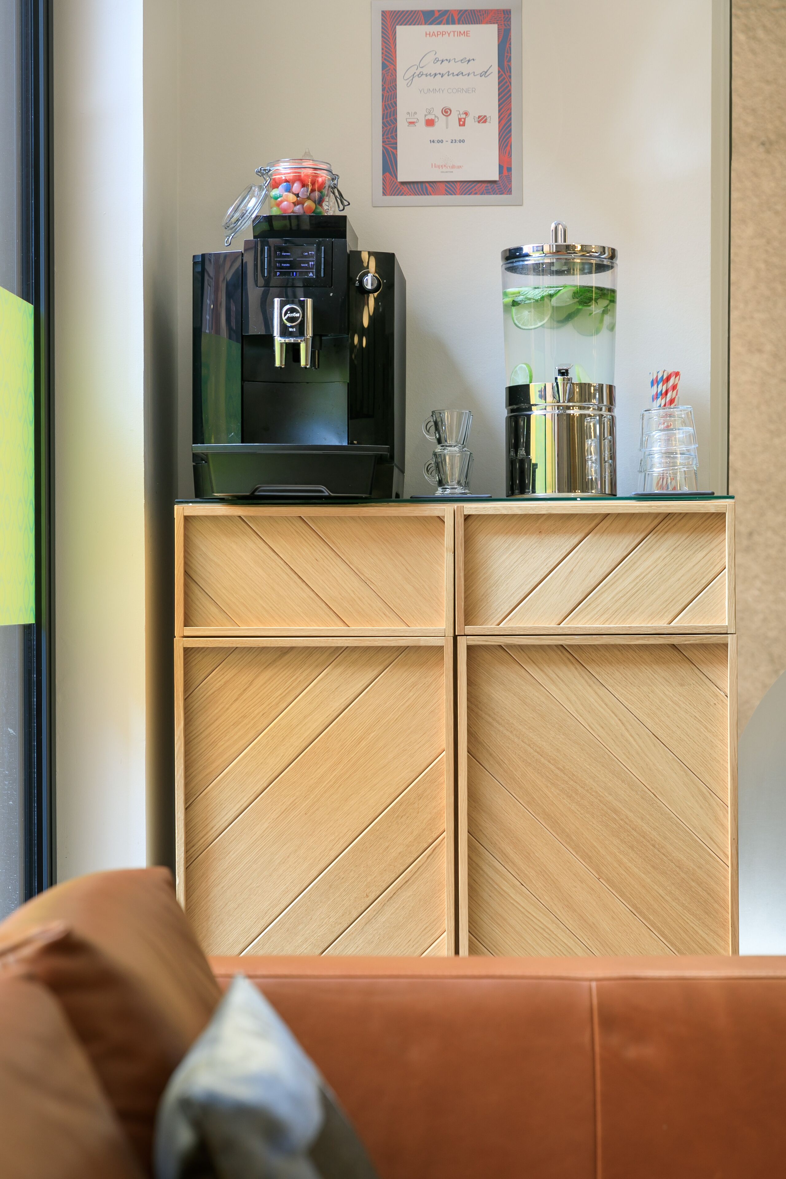 Máquina de café, bebedouro e dispensador de suco sobre um armário de madeira.