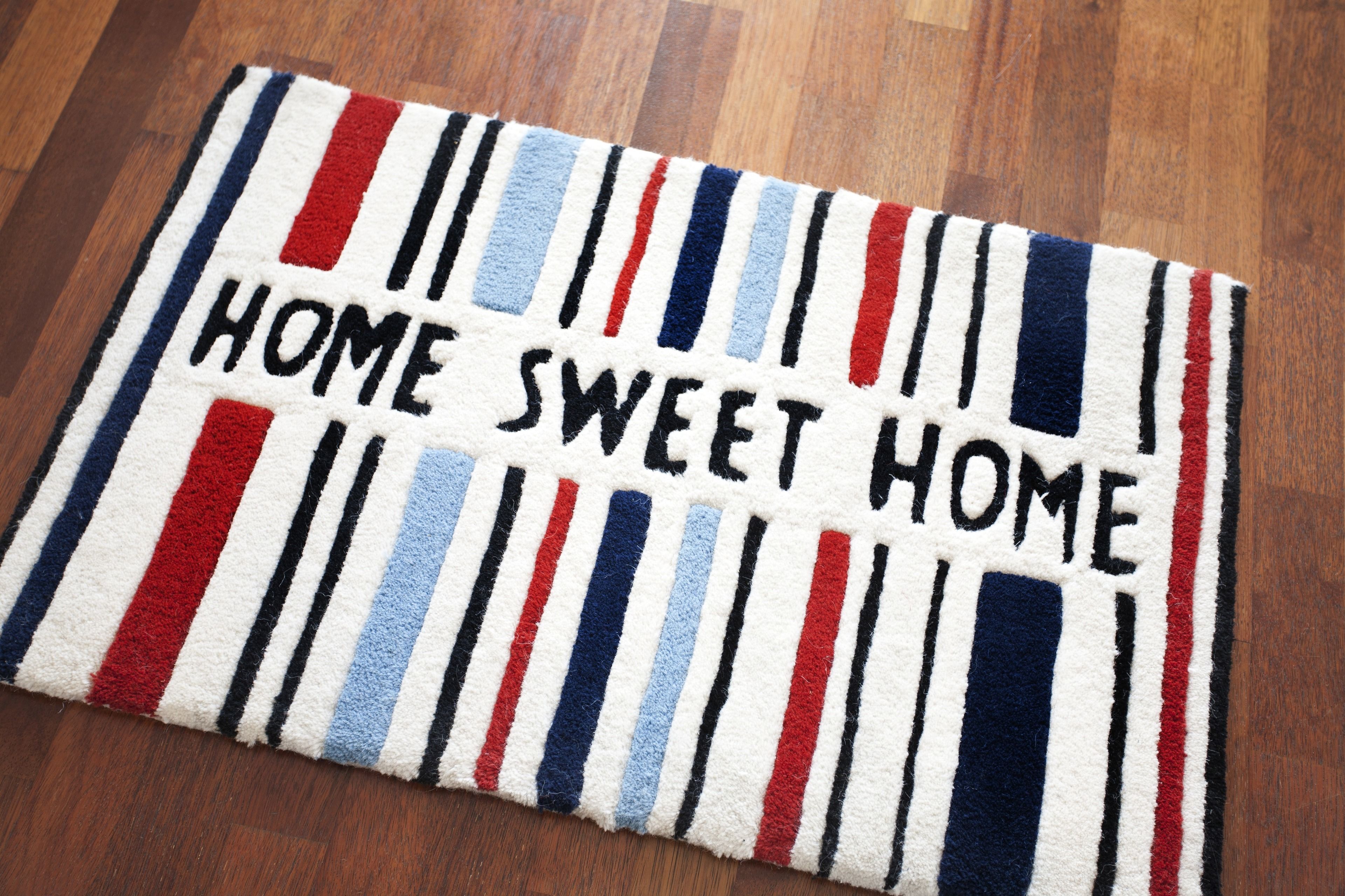 Tapete listrado com a inscrição 'HOME SWEET HOME' sobre um piso de madeira.