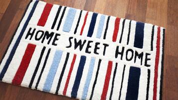 Tapete listrado com a inscrição 'HOME SWEET HOME' sobre um piso de madeira.