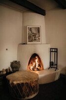 Uma lareira com fogo, um quadro emoldurado acima e uma pequena mesa na frente.