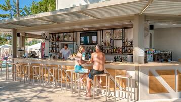 Uma área externa com bar, balcão, assentos e diversas garrafas.