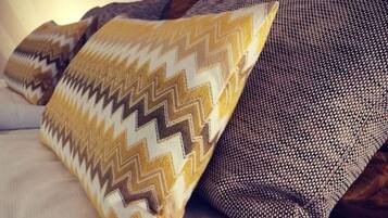 Uma cama com almofadas estampadas e um cobertor texturizado.
