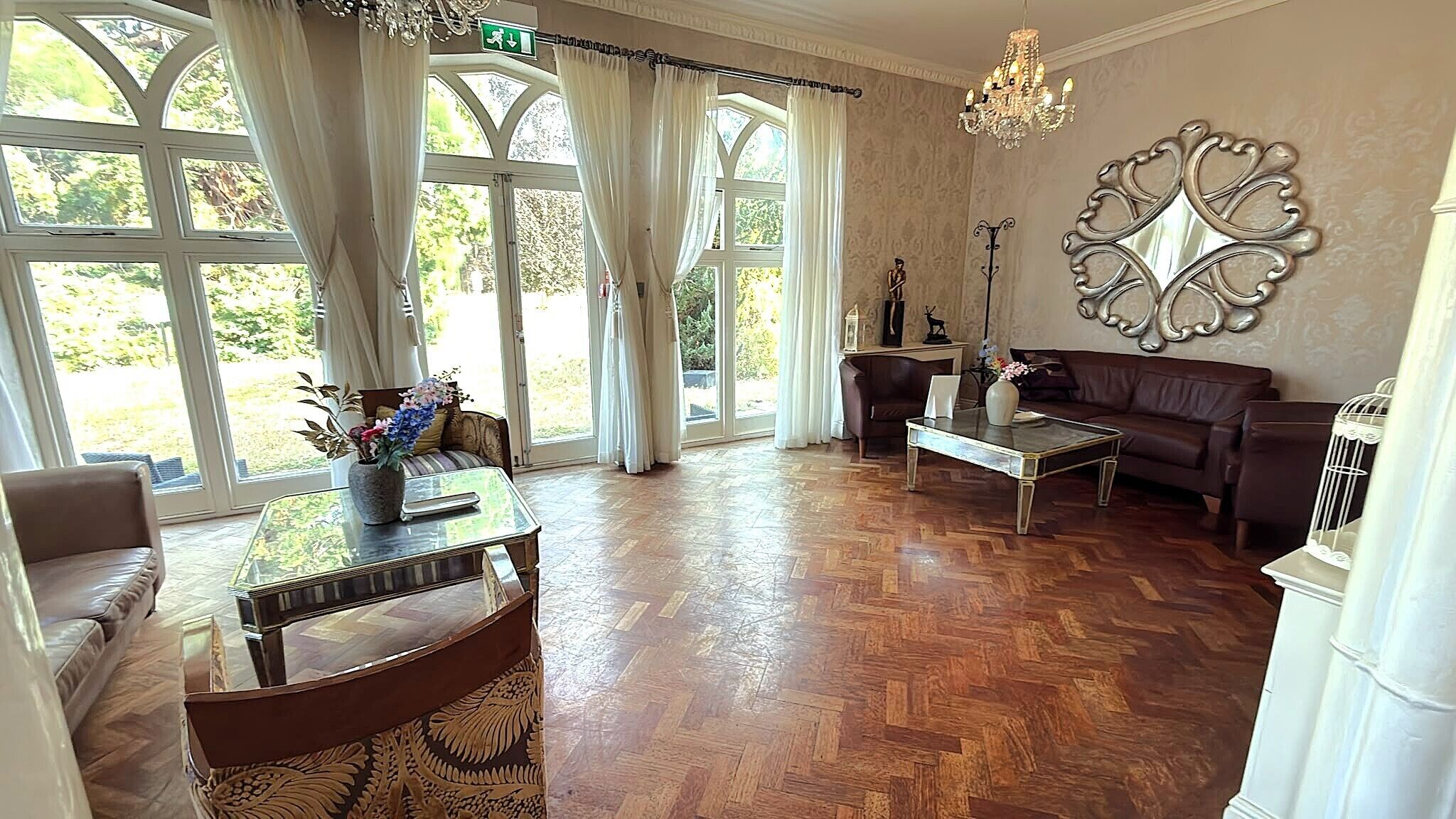 Um quarto amplo com uma grande janela, um candelabro, um sofá e uma mesa de centro.
