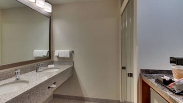 Casa de banho de hotel com duas pias, um espelho grande e zona de duche.
