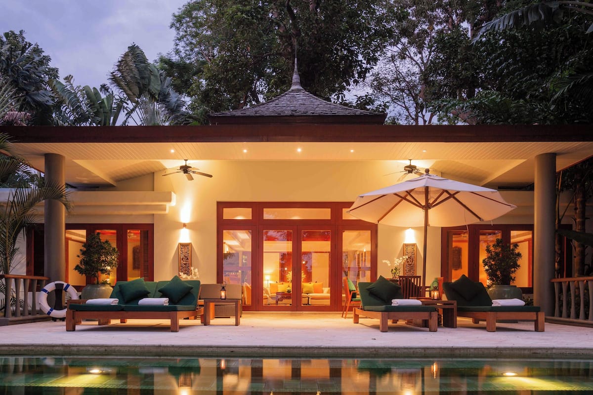 Resort com piscina, espreguiçadeiras e área de estar coberta.