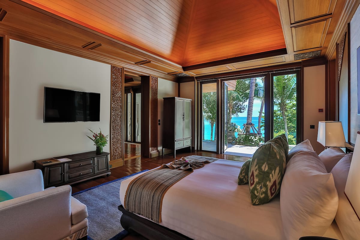 Um quarto espaçoso com uma cama grande, televisão, armário e vista para o mar.