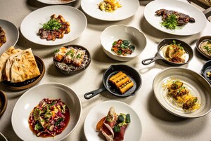 Diversos pratos sobre uma mesa, incluindo bife, massa e legumes.