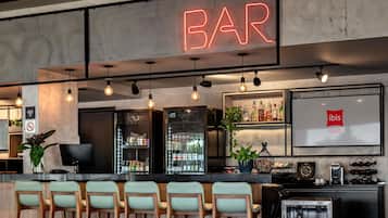 Uma área de bar com um letreiro de neon, assentos e uma variedade de bebidas.
