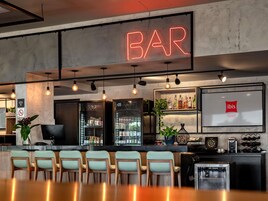Uma área de bar com um letreiro de neon, assentos e uma variedade de bebidas.