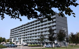 Um edifício com vários andares, varandas, estacionamento e céu limpo.