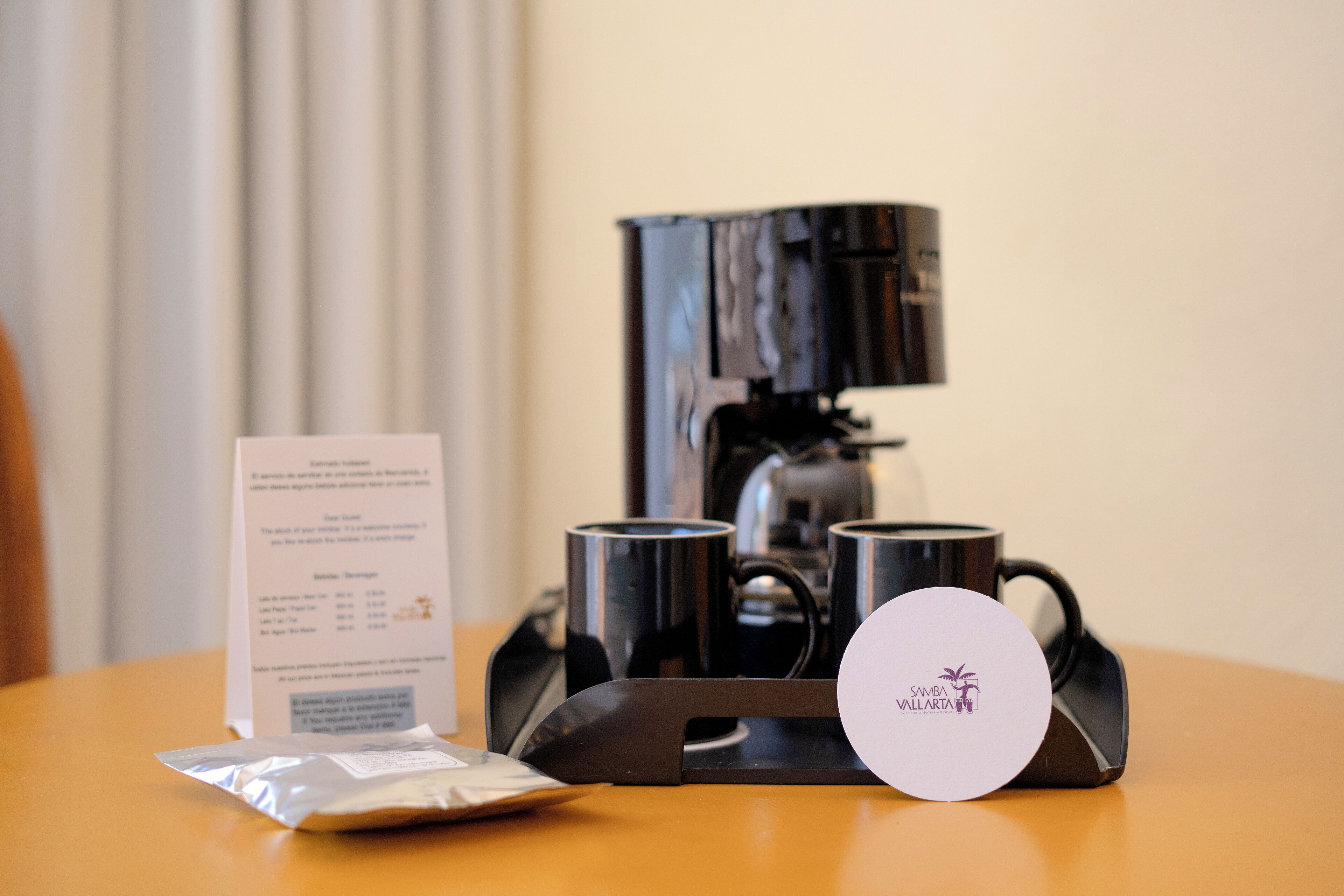 Uma máquina de café com duas chávenas e um café em cápsula numa mesa.