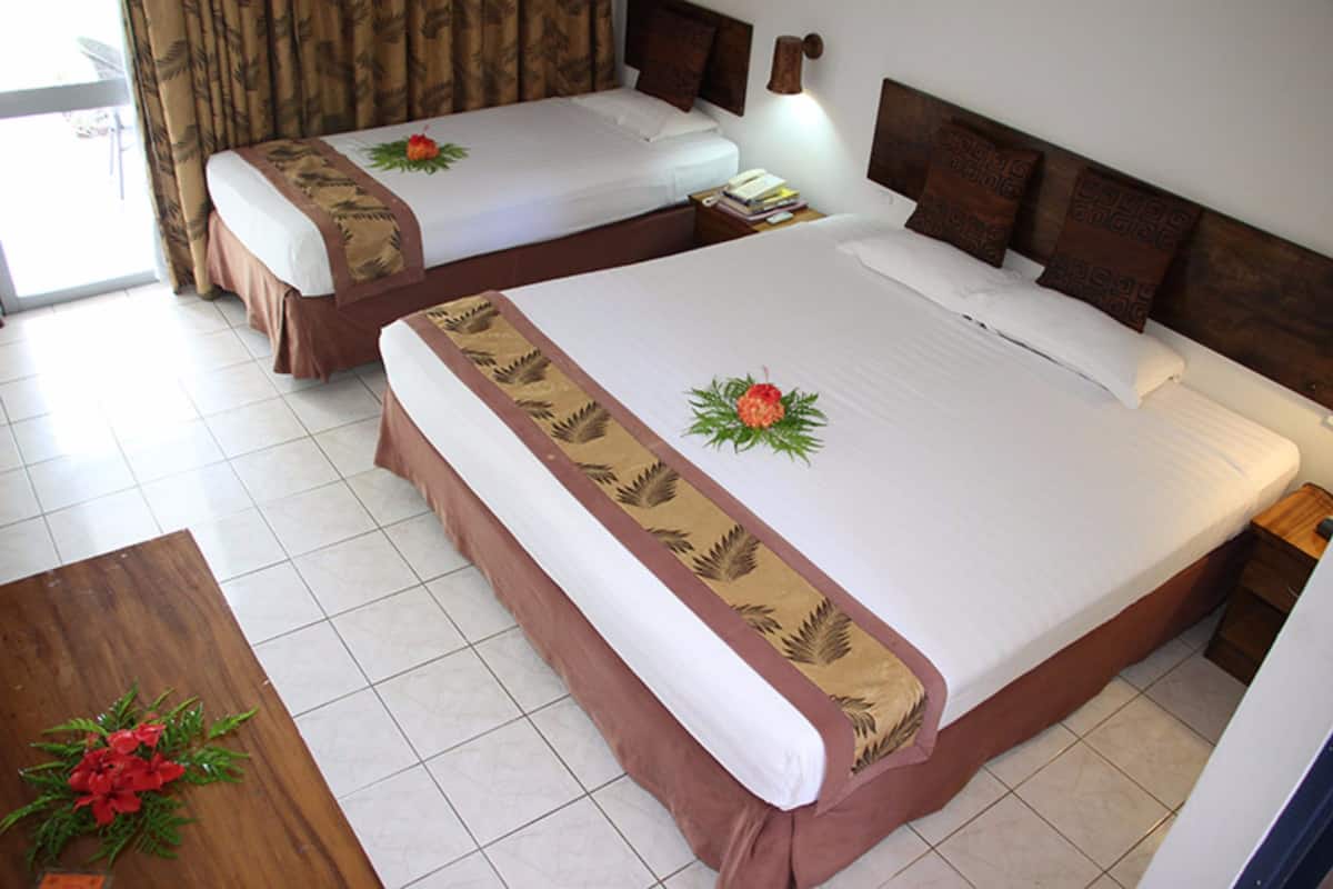 Quarto de hotel com duas camas, cada uma com colcha floral e cabeceira marrom.