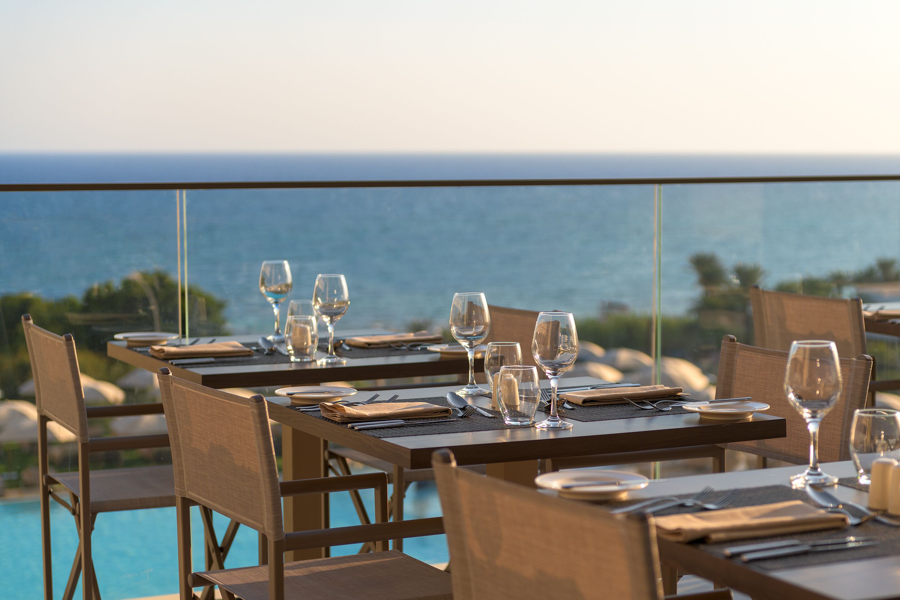 Mesa de jantar posta com cadeiras, com vista para uma piscina e o oceano.