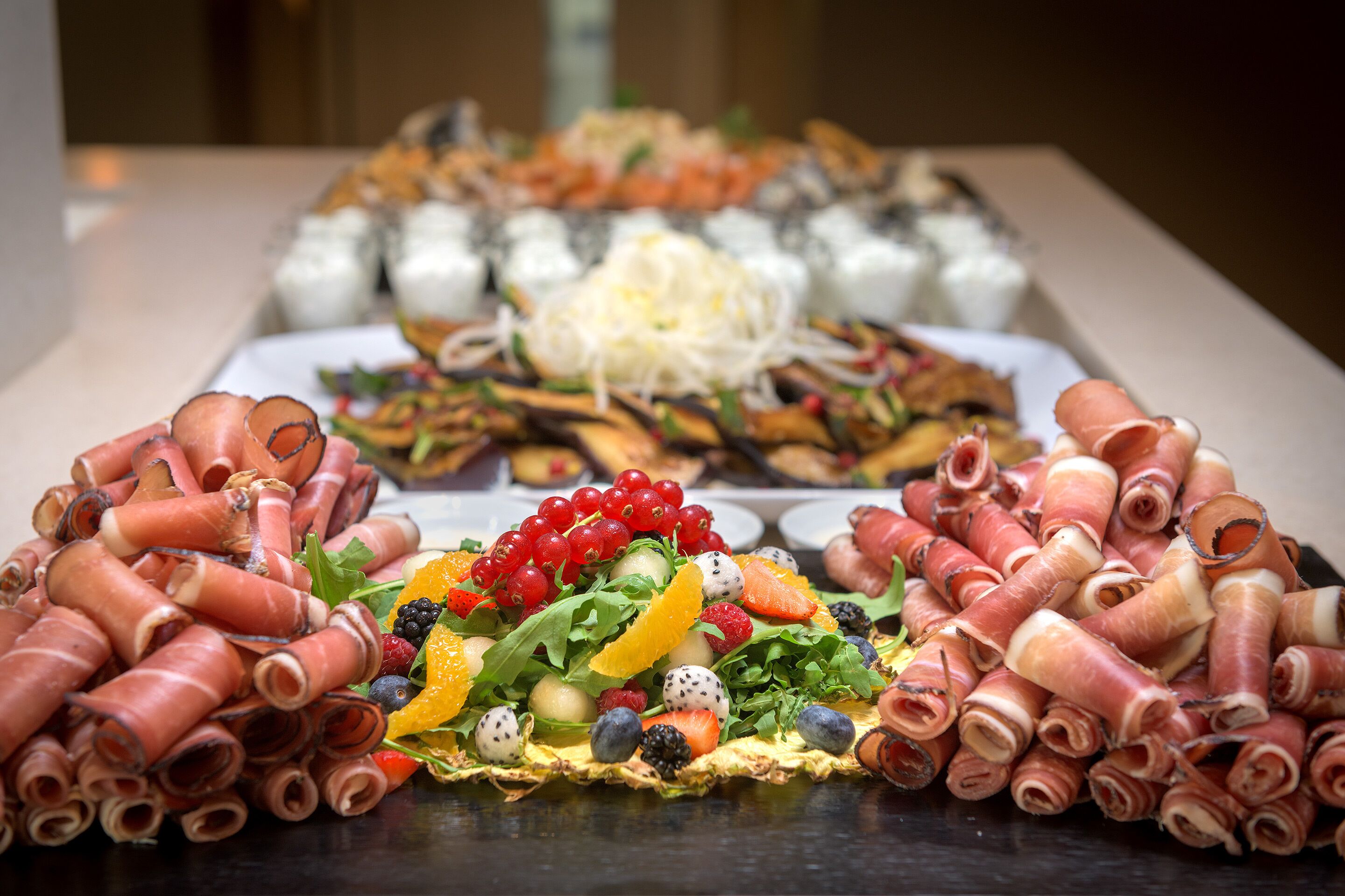 Buffet com diversos alimentos, incluindo carnes, frutas e vegetais.