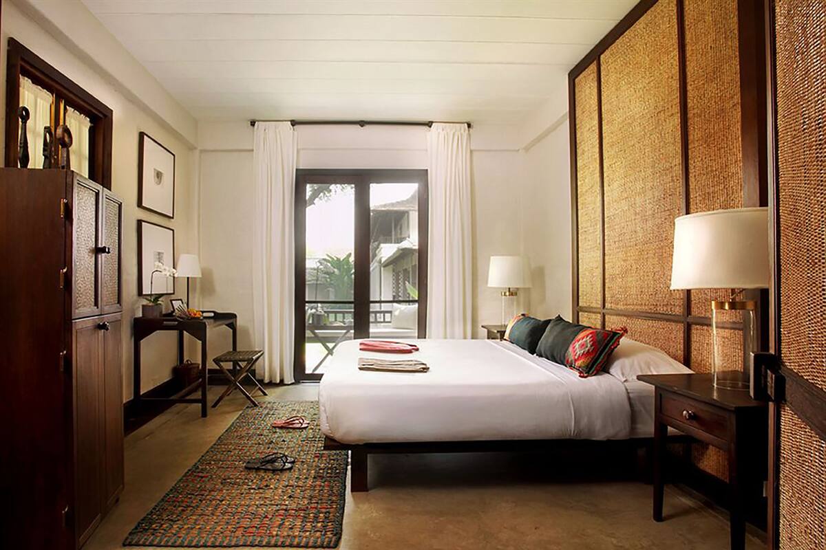 Quarto de hotel com cama, mesas de cabeceira, escrivaninha e vista para o exterior.