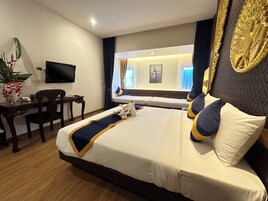 Quarto de hotel com uma cama grande, uma mesa, uma cadeira, uma televisão e uma janela com cortinas.
