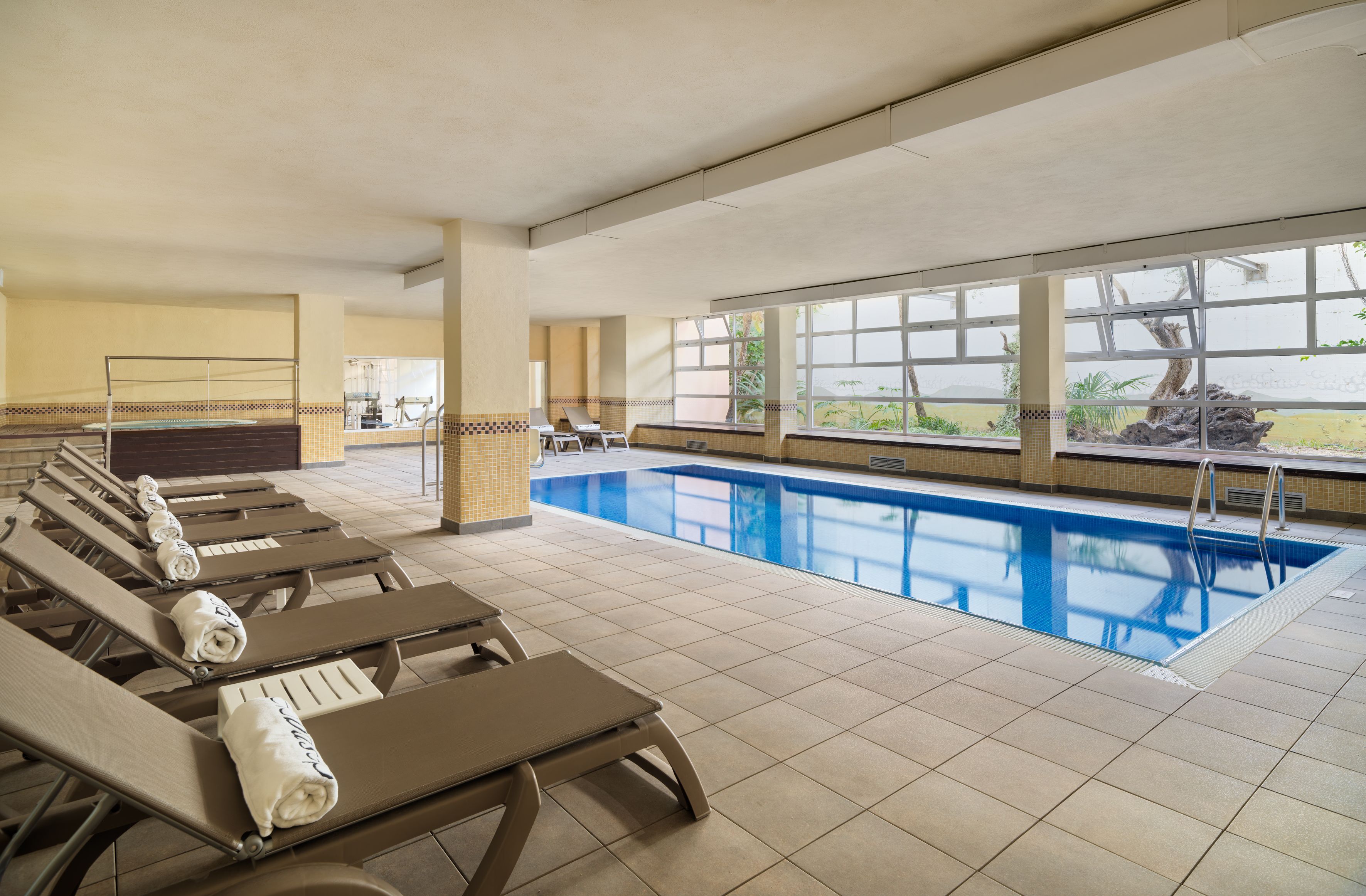 Área da piscina com espreguiçadeiras e vista para o exterior.
