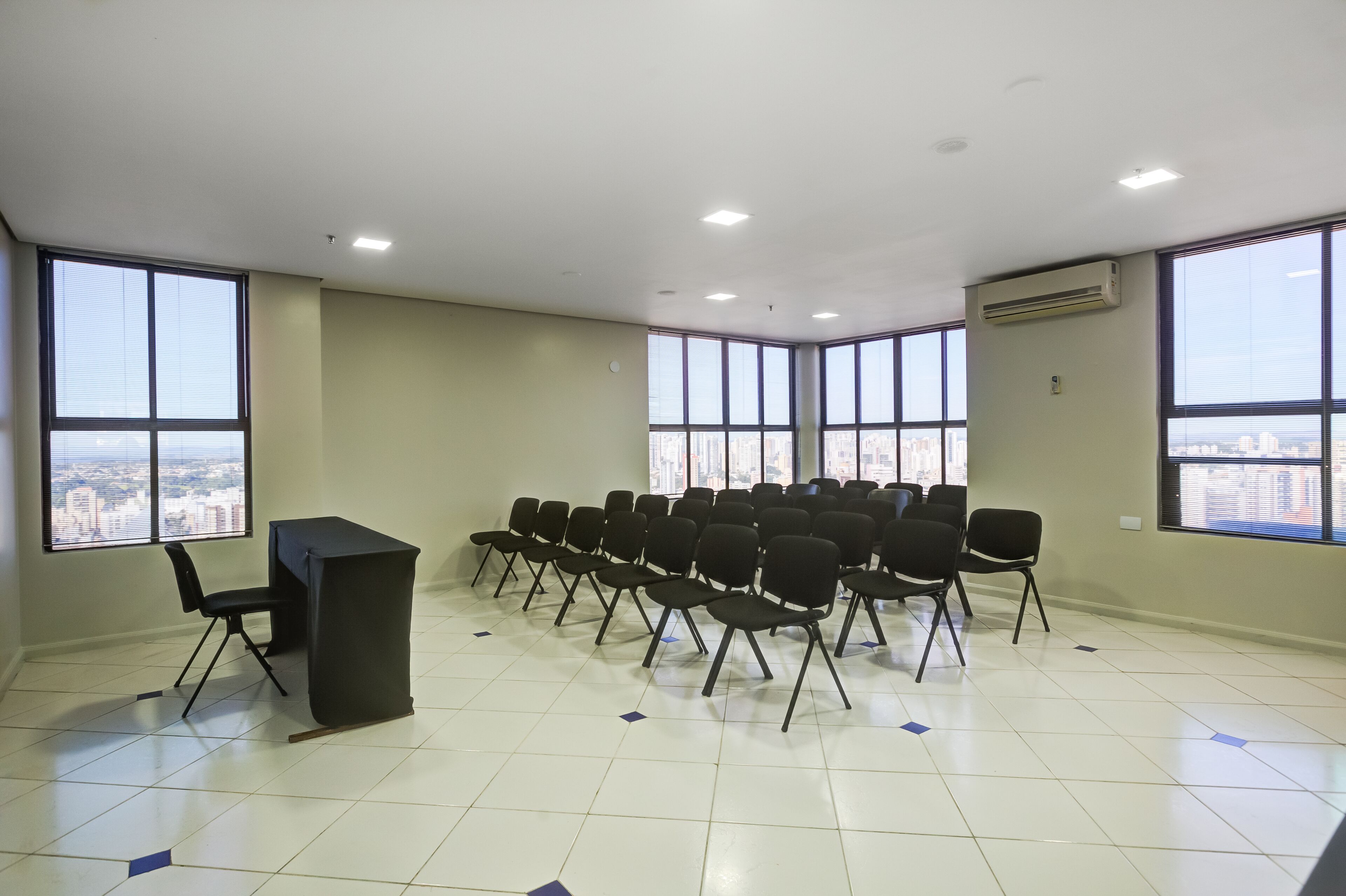 Uma sala de conferências com teto alto, janelas amplas e uma fileira de cadeiras.
