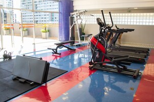 Uma academia com esteiras, um banco de musculação e equipamentos de ginástica.