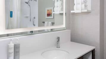Casa de banho moderna com um espelho grande, lavatório branco e duas embalagens de loção corporal Zero.