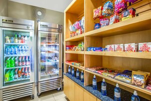 Uma área de distribuição automática com diversos petiscos e bebidas, incluindo Welch's e JackLink's, e dois refrigeradores com bebidas.