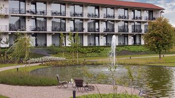 Hotel com vários andares, varandas, lago e área de estar ao ar livre.