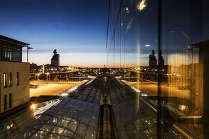 Um edifício moderno com fachada de vidro e vista para a paisagem urbana ao anoitecer.