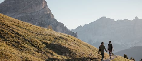 Paisagem montanhosa com um caminho bem definido e duas pessoas caminhando.