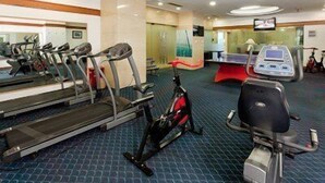 Uma academia com esteiras, bicicletas ergométricas e um remo.