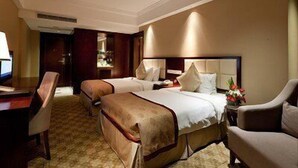 Quarto de hotel com duas camas, uma escrivaninha, uma cadeira e uma mesa de cabeceira.