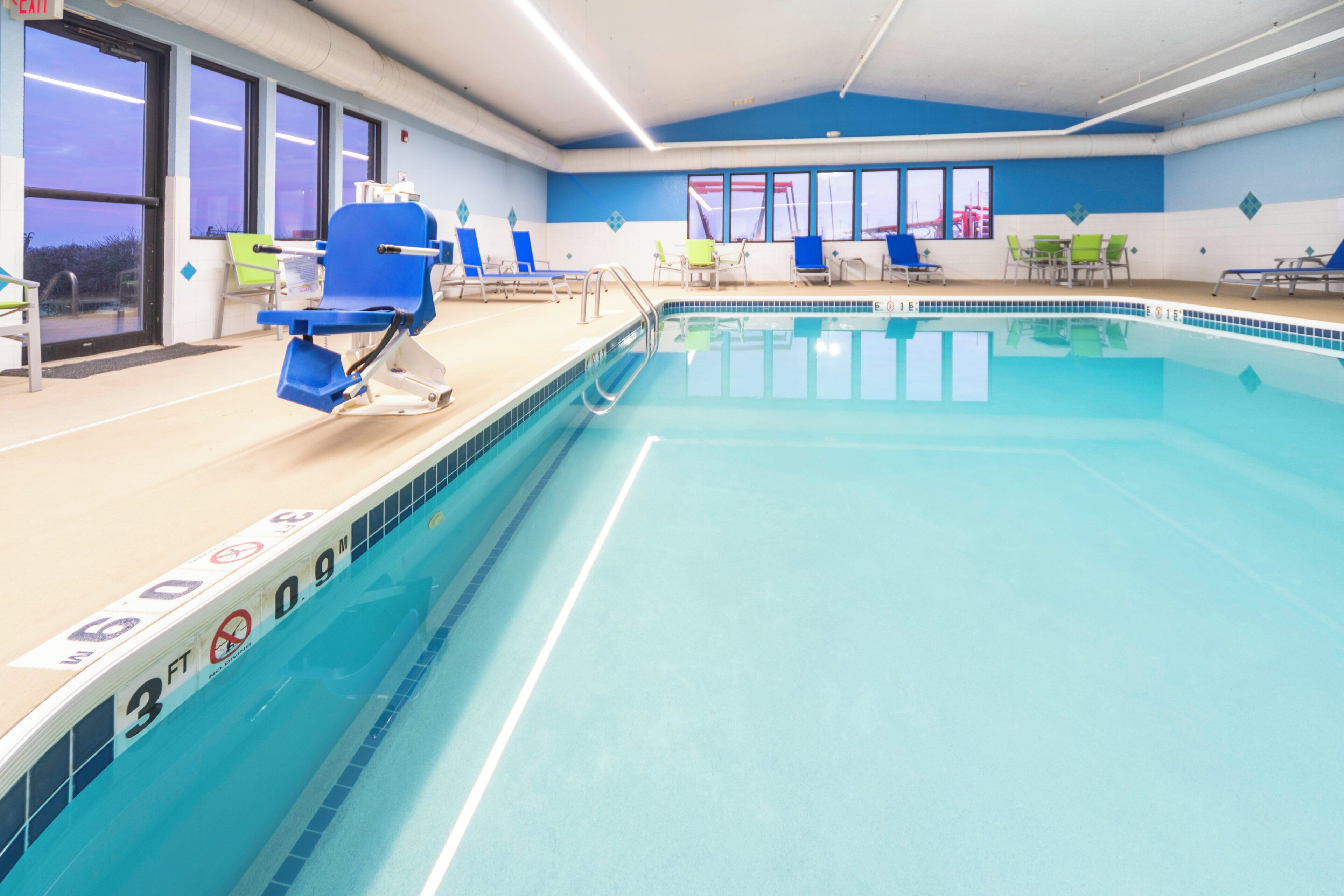Piscina interna com água cristalina, pistas demarcadas e cadeira do salva-vidas.