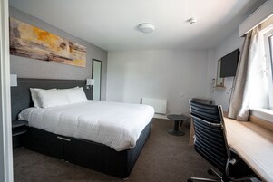 Quarto de hotel moderno com uma cama grande, uma escrivaninha e uma cadeira.