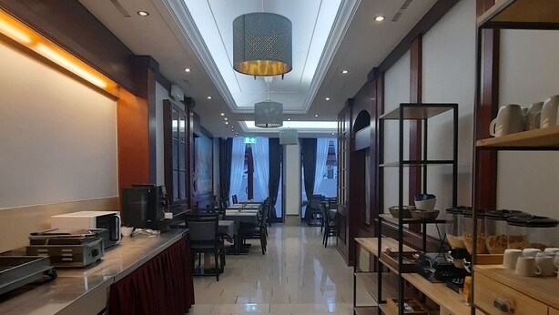 Um hall de hotel moderno com um balcão de recepção extenso, um candelabro e vista da cidade através de grandes janelas.
