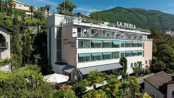 Um hotel com várias andares chamado "La Perla", com varandas, área externa para sentar e vegetação exuberante ao redor.