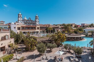 Um resort com piscina, áreas de lazer e um edifício imponente com torres.