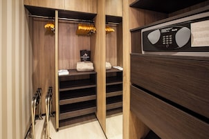 Quarto de hotel com armário de madeira, minibar e painel de controle do minibar.