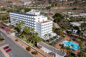 Hotel com design moderno, apresentando piscina no terraço e várias varandas.