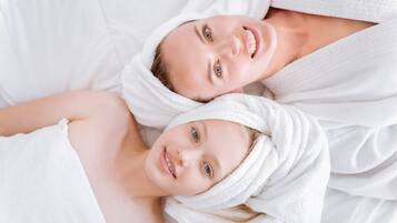 Uma pessoa vestindo um roupão branco, deitada, sugerindo um ambiente de spa ou relaxamento.