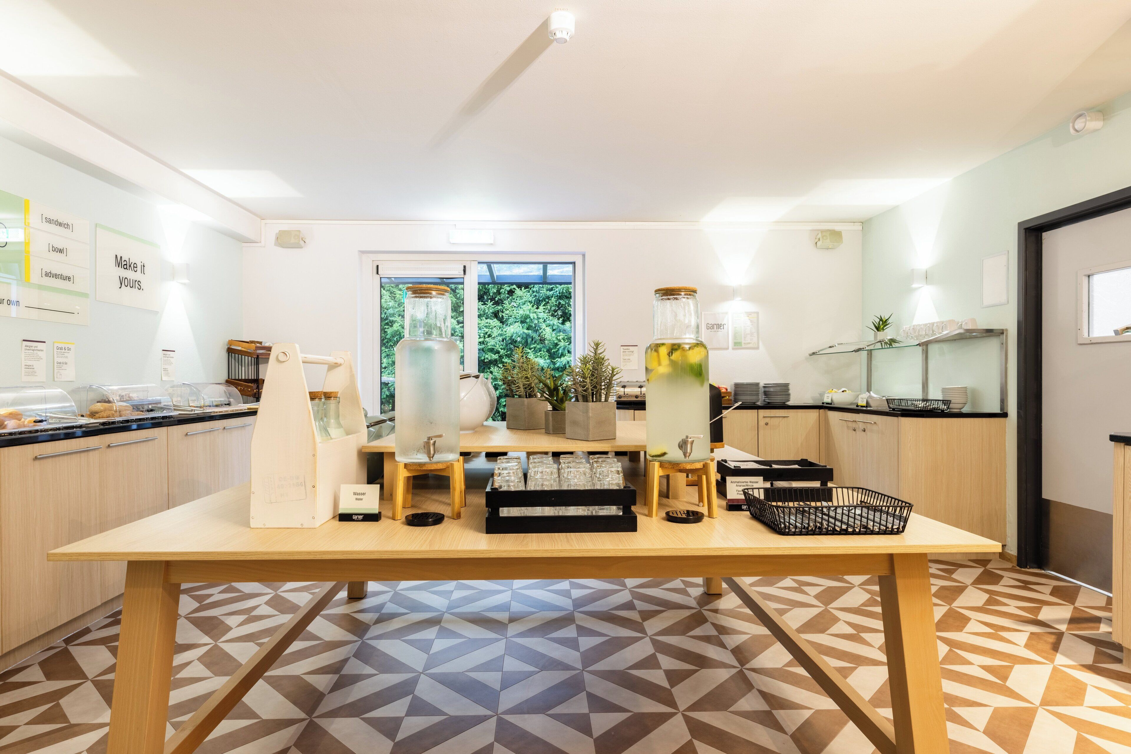 Cozinha moderna com ilha central, janela com vista para área verde e piso com padrão geométrico.