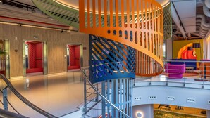 Um interior moderno com escada em espiral, portas vermelhas e um espaço de recreação colorido.