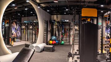 Uma academia com diversos equipamentos de exercício, incluindo aparelhos de musculação, bancos e bolas de ginástica.