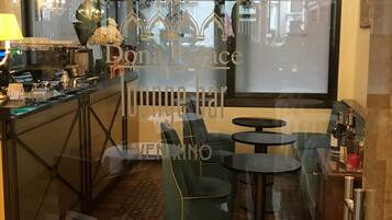 Um bar de lounge com piso xadrez, um candelabro e vista para um edifício através de uma janela.