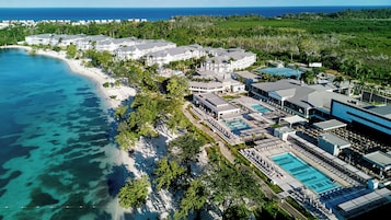 Vista aérea de um resort com vários edifícios, uma praia e área de piscina.